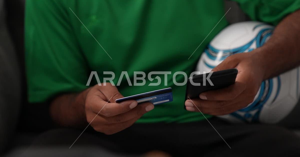 Close-up of two Saudi Arabian Gulf youths using a mobile phone, using a ...