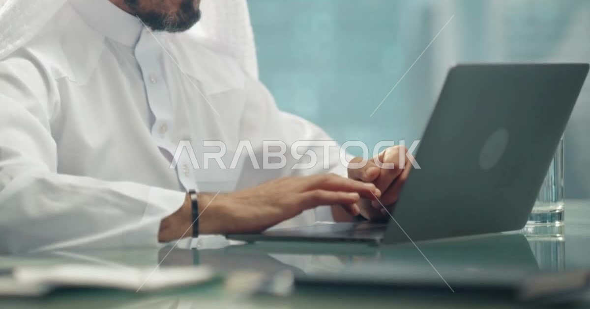 A Saudi Arabian Gulf man using a laptop, working remotely, using modern ...