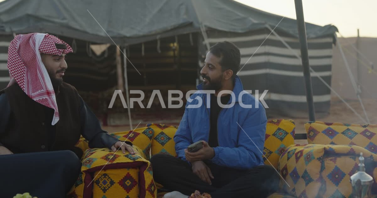 Two Saudi Arabian Gulf men dressed in warm winter clothes and browsing ...