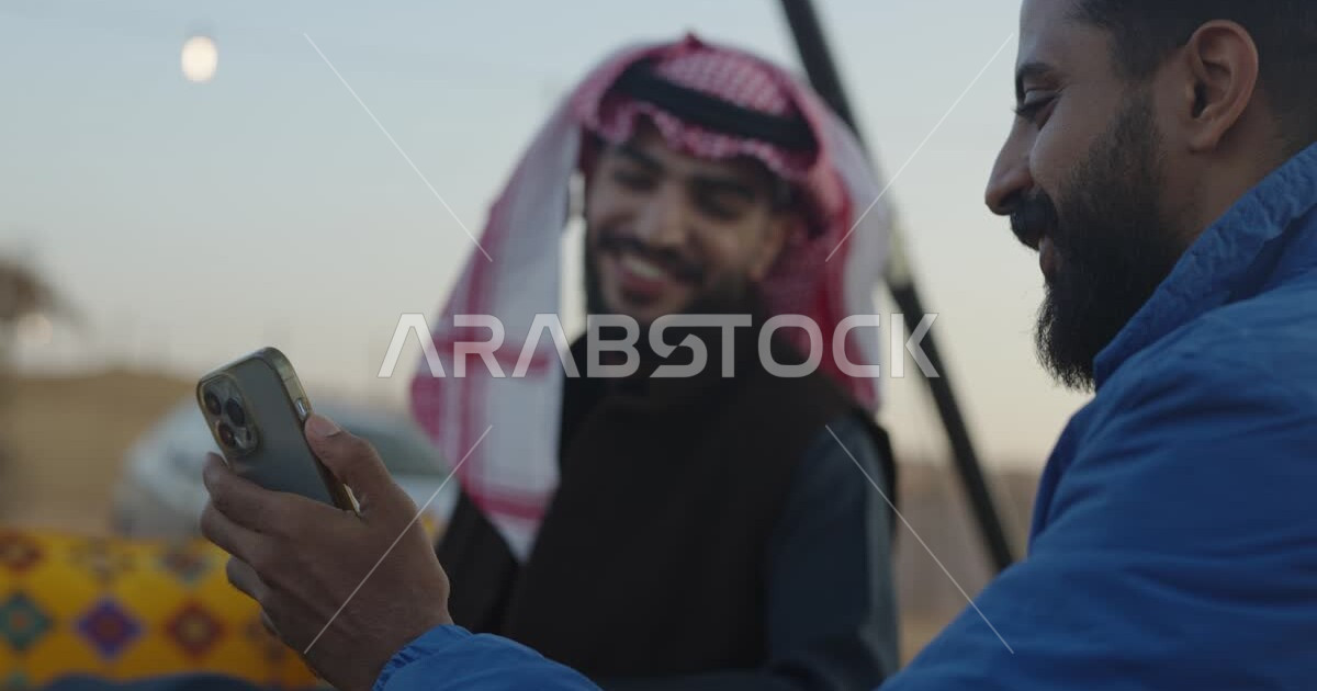 Two Saudi Arabian Gulf men dressed in warm winter clothes and browsing ...