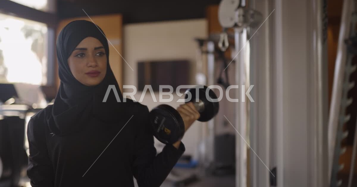 A veiled Saudi Arab Gulf woman in the sports club, exercising with ...