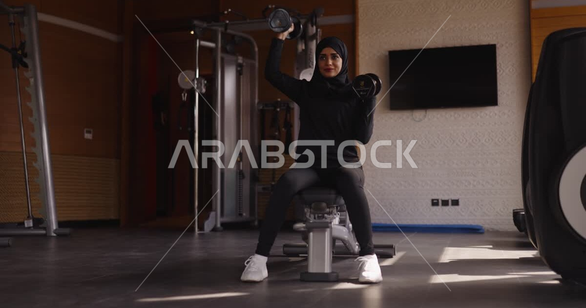 A veiled Saudi Arab Gulf woman in the sports club, exercising with ...