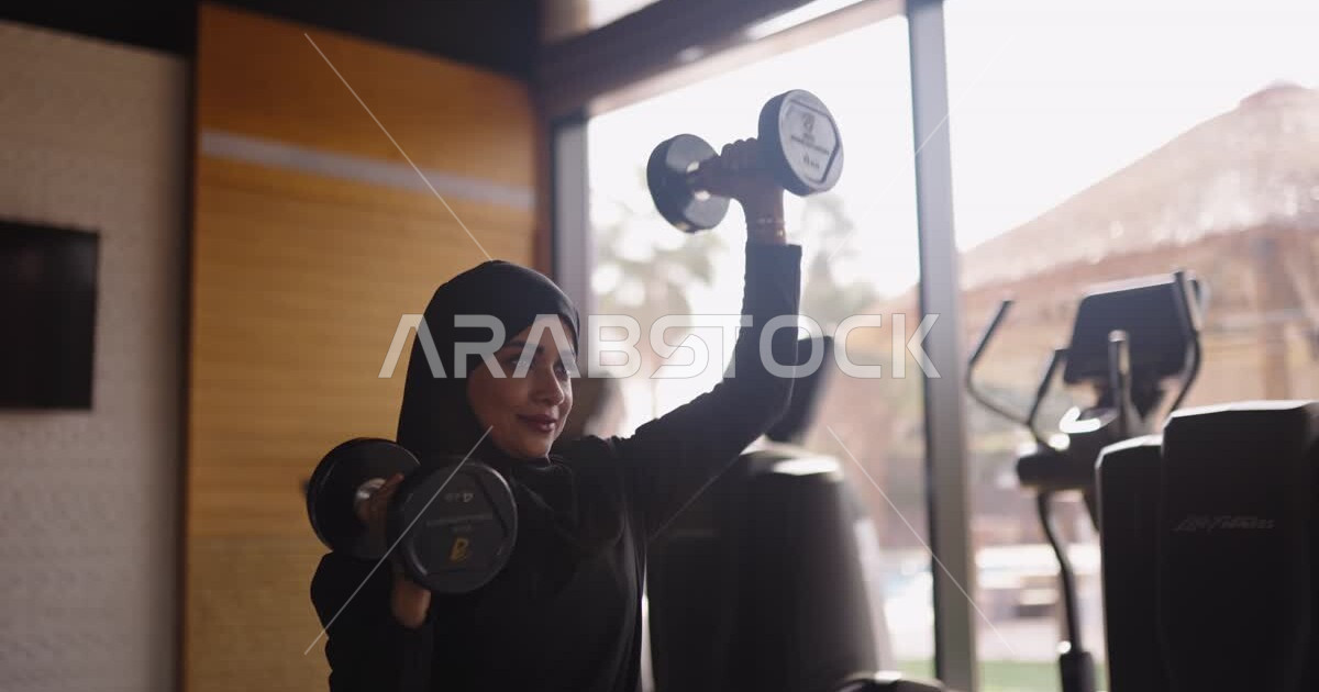 A veiled Saudi Arab Gulf woman in the sports club, exercising with ...