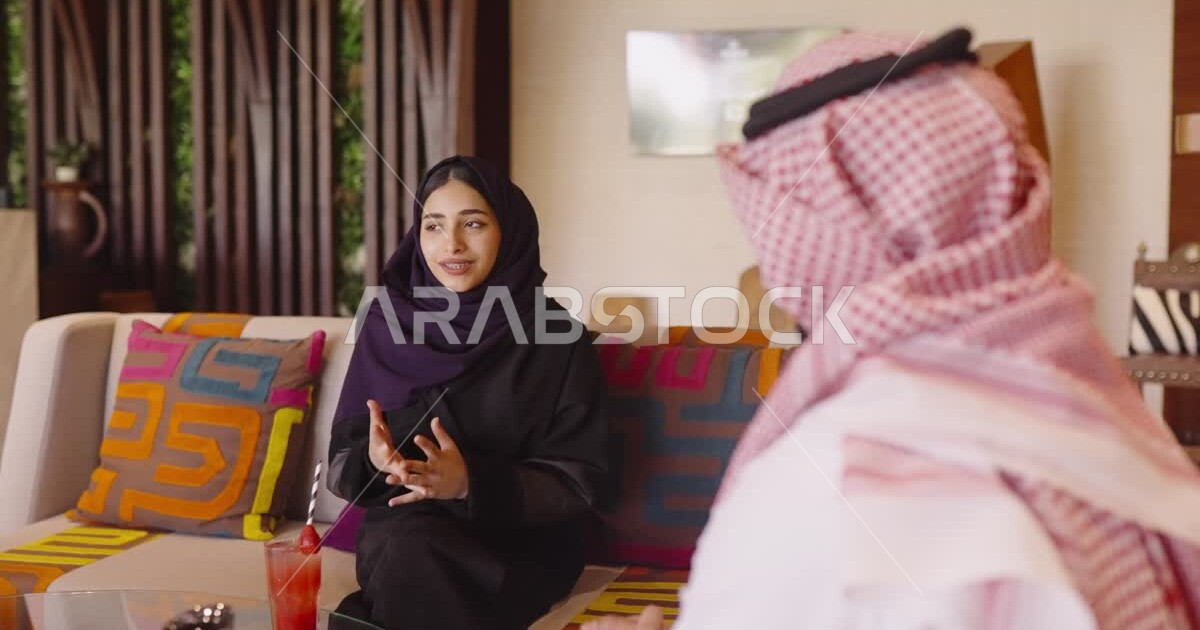 رجل وإمرأه عربيان سعوديان خليجيان يجلسان في مقهى عصري الإستمتاع بشرب