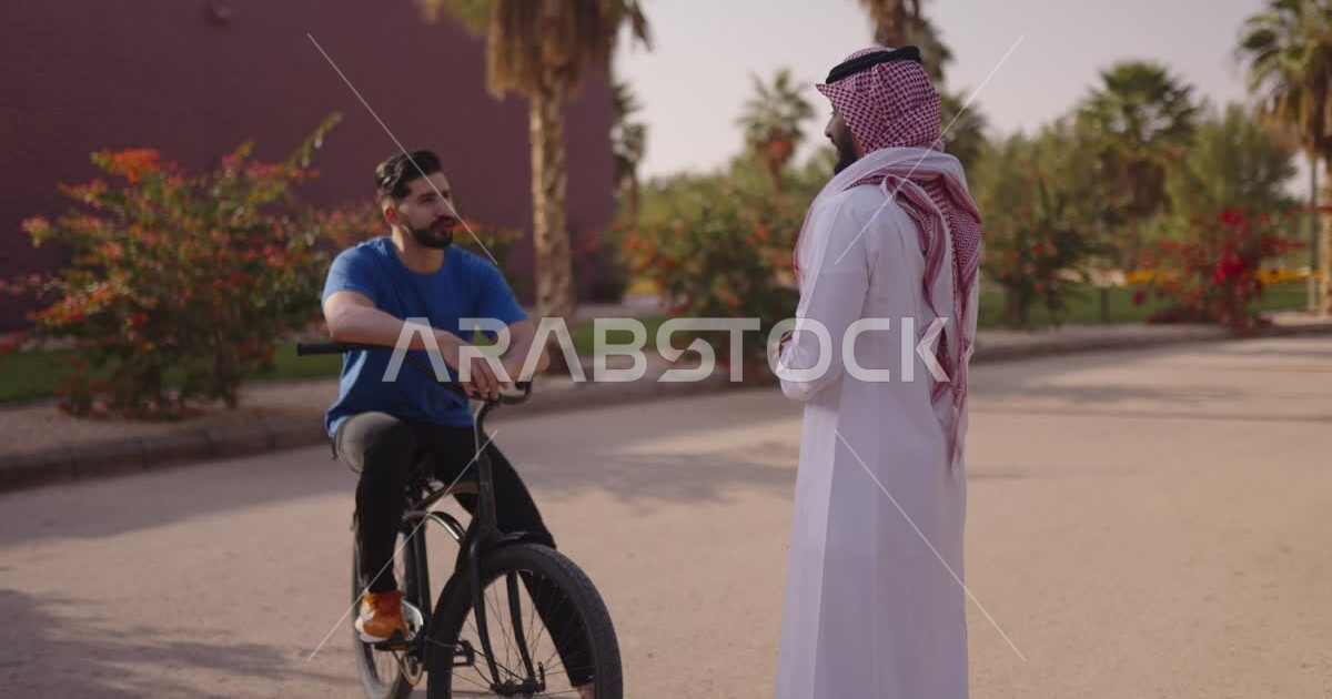 An Arab young man wearing casual attire riding a bicycle talking with a ...