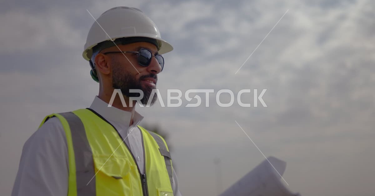 An Arab Gulf Saudi engineer, wearing sunglasses, a helmet and a work ...