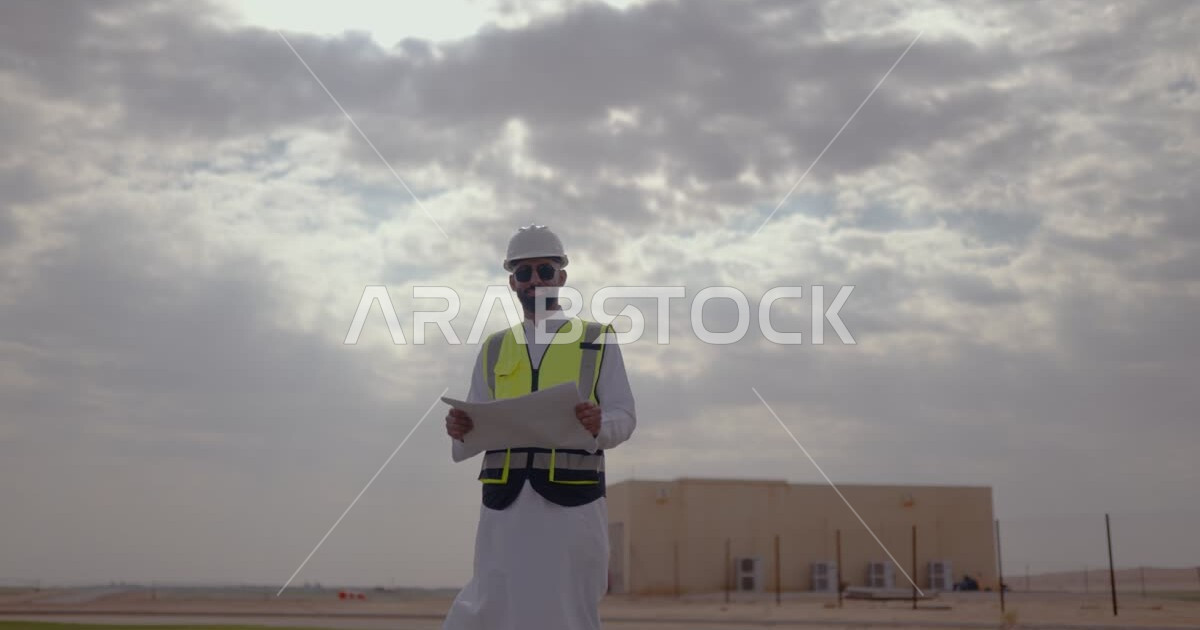 An Arab Gulf Saudi engineer, wearing sunglasses, a helmet and a work ...