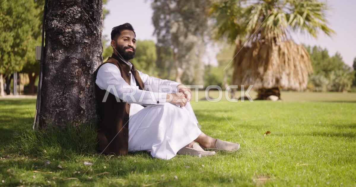 A Saudi Arabian Gulf man sitting under a tree, public parks, meditation ...