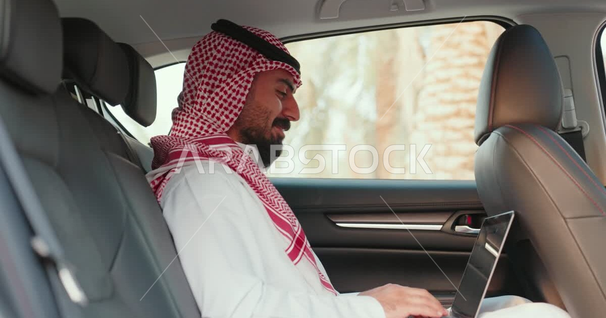 A Saudi Arabian Gulf man sitting in the car and using a laptop, surfing ...