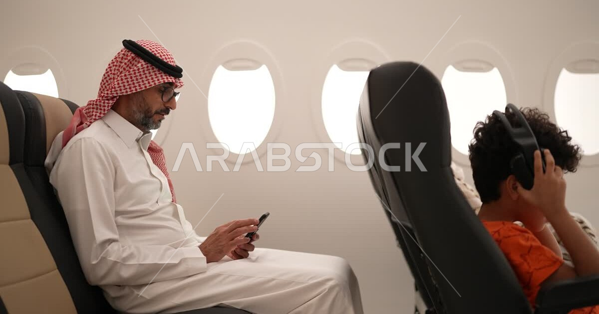 A Saudi Gulf Arab family inside the plane, using a mobile phone, family ...