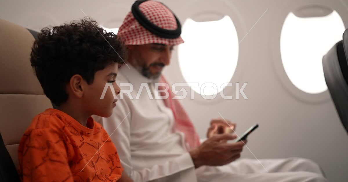 A Saudi Gulf Arab family inside the plane, using a mobile phone, family ...