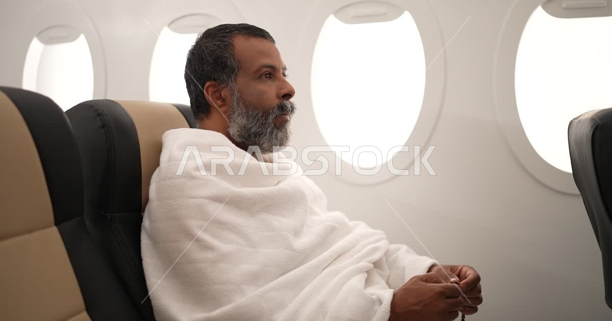 A Saudi Arabian Gulf man from inside the plane, wearing the Ihram dress ...
