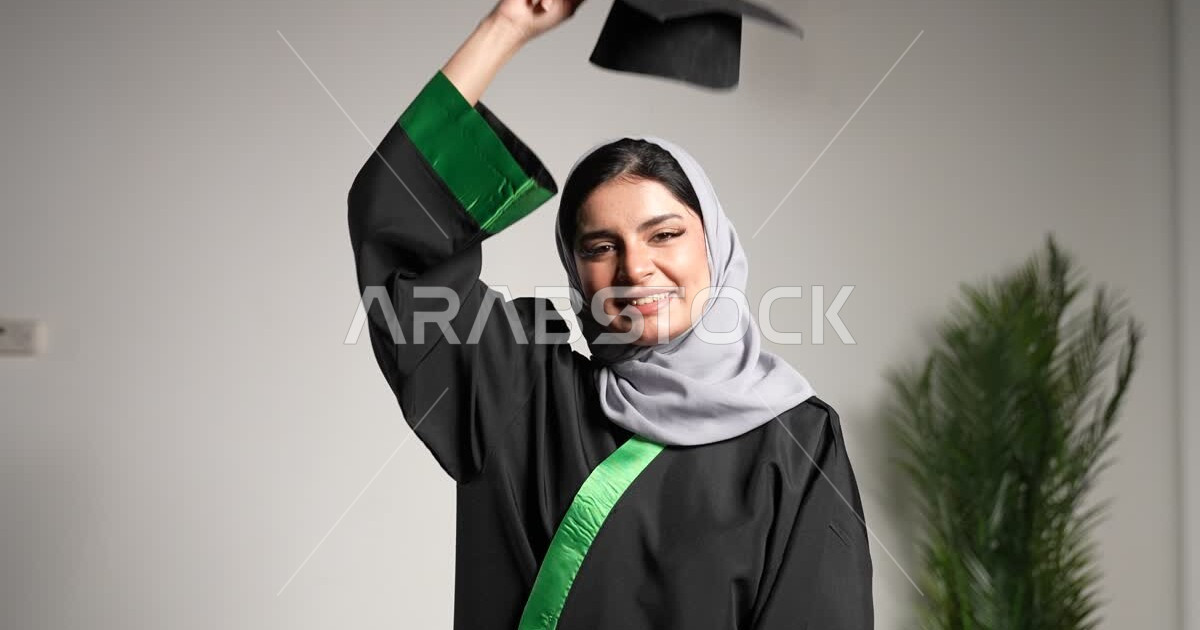Smiling Saudi Arab Gulf woman, wearing a graduation gown, academic ...