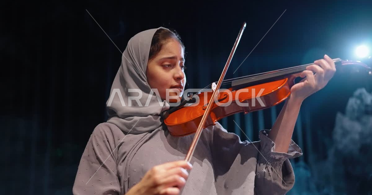 A Saudi Gulf Arab woman playing the violin, spending pleasant times ...