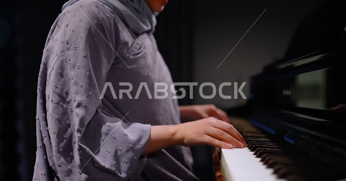 A Saudi Gulf Arab woman playing the piano, spending pleasant times ...