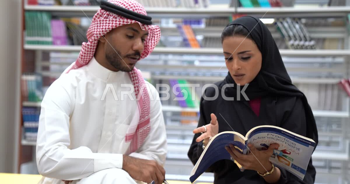 Two Saudi Arabian Gulf students in the university library, reading a ...