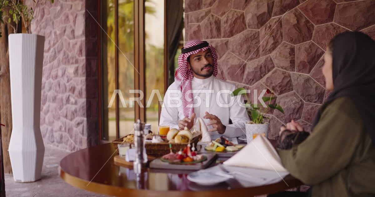 A Saudi Arabian Gulf couple sitting in the restaurant, a meal full of ...