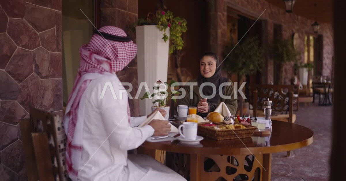 A Saudi Arabian Gulf couple sitting in the restaurant, a meal full of ...