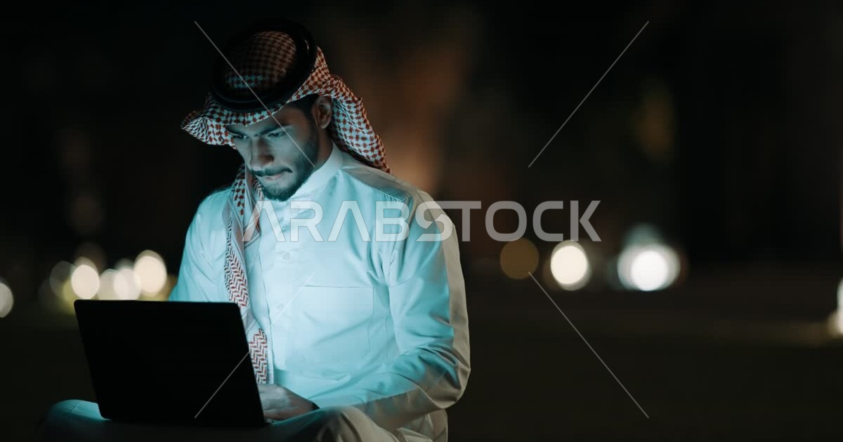 A Saudi Arabian Gulf man wearing traditional Saudi dress working on a ...