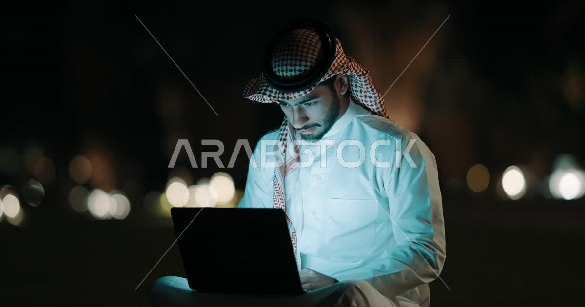 A Saudi Arabian Gulf man wearing traditional Saudi dress working on a ...