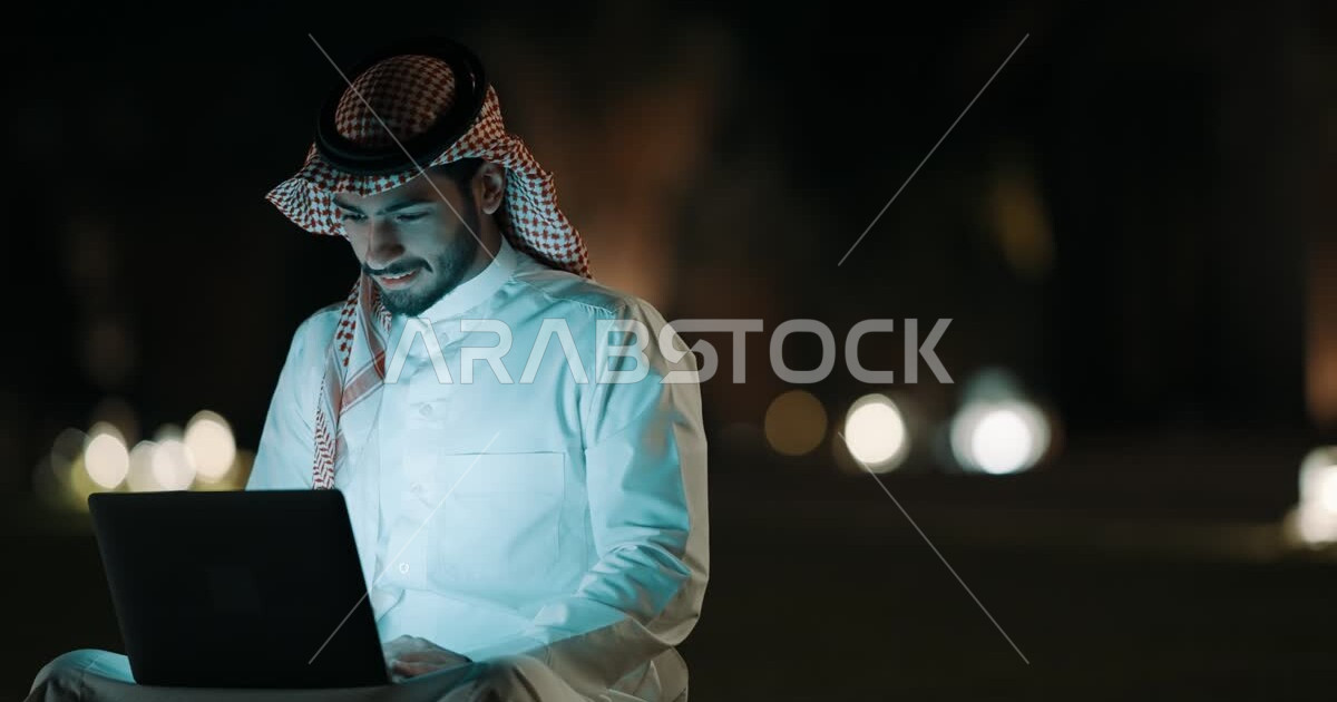 A Saudi Arabian Gulf man wearing traditional Saudi dress working on a ...