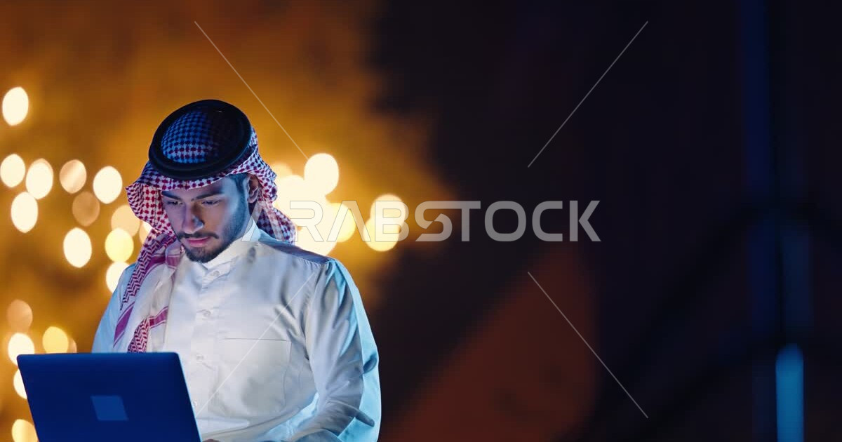 A Saudi Arabian Gulf man wearing traditional Saudi dress working on a ...