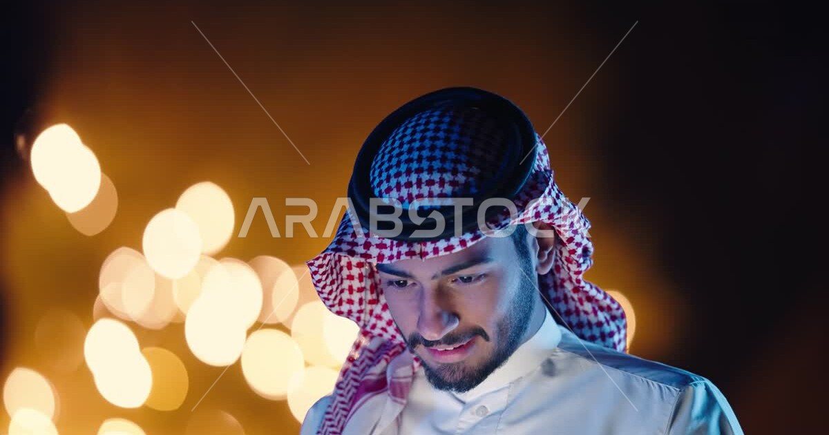A Saudi Arabian Gulf man wearing traditional Saudi dress working on a ...