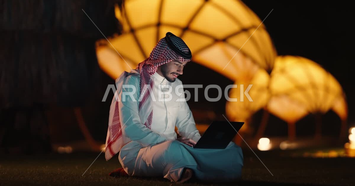 A Saudi Arabian Gulf man wearing traditional Saudi dress working on a ...