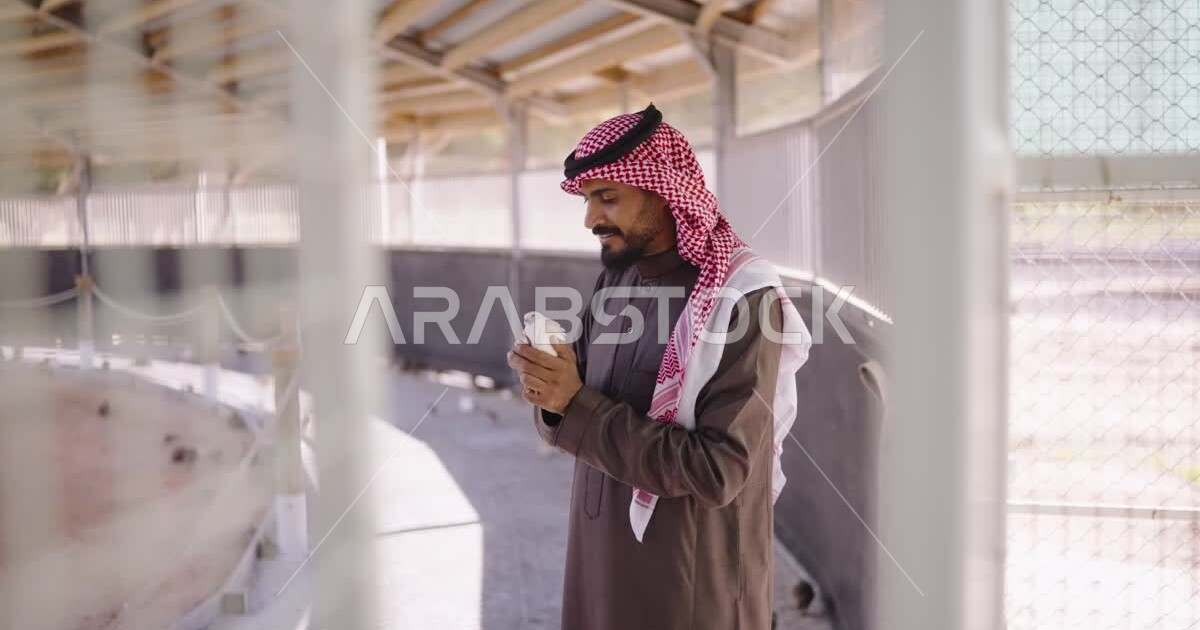 A Saudi Arabian Gulf man, dressed in traditional Saudi dress, spending ...