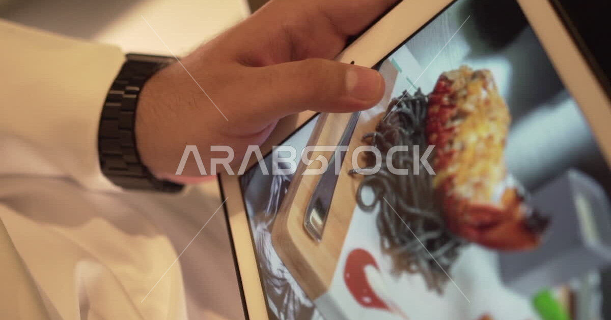 Close-up of a man using a tablet technology device to choose a meal ...