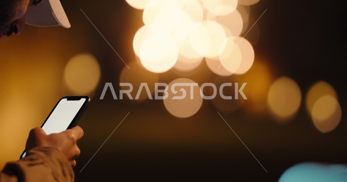 Close-up of a Saudi Arabian Gulf man, using a mobile phone, surfing the ...