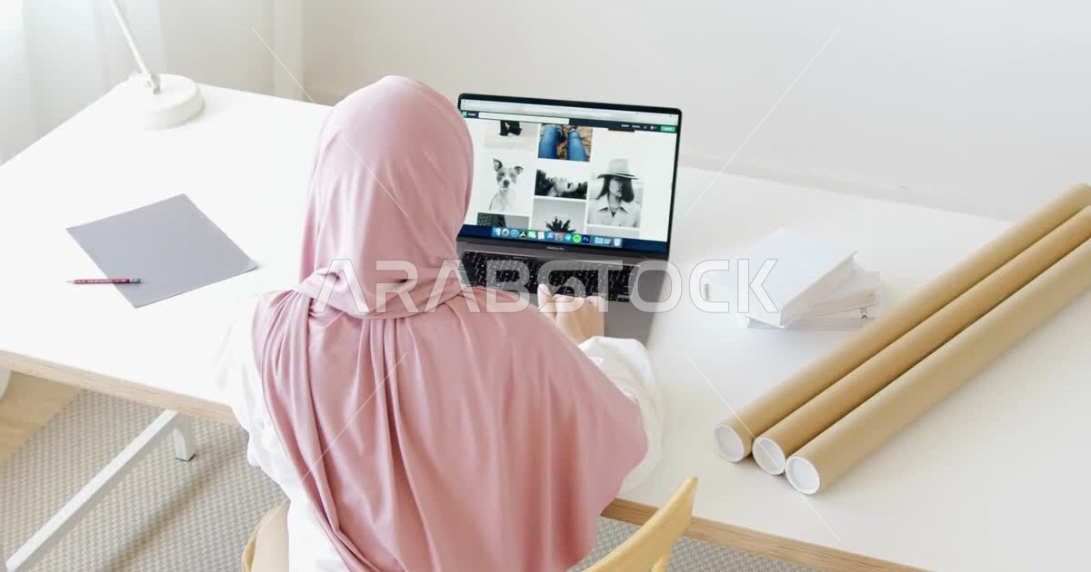 Photography from behind of a veiled Arab woman working on a computer ...