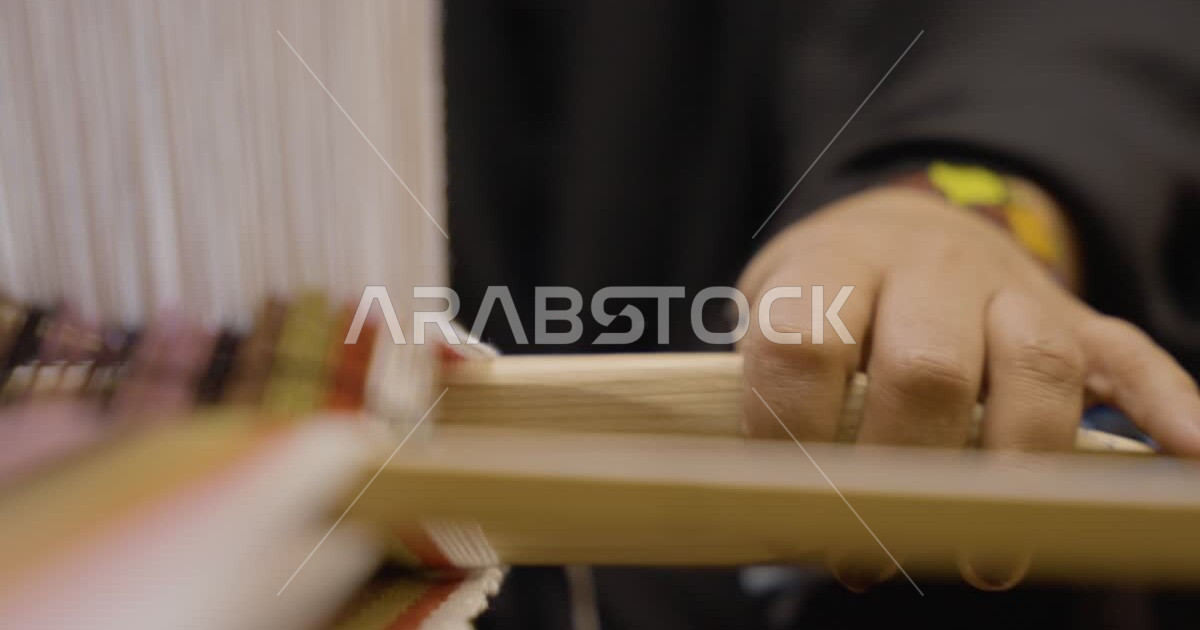 Close-up of the hand of a Saudi Arabian Gulf woman weaving and spinning ...