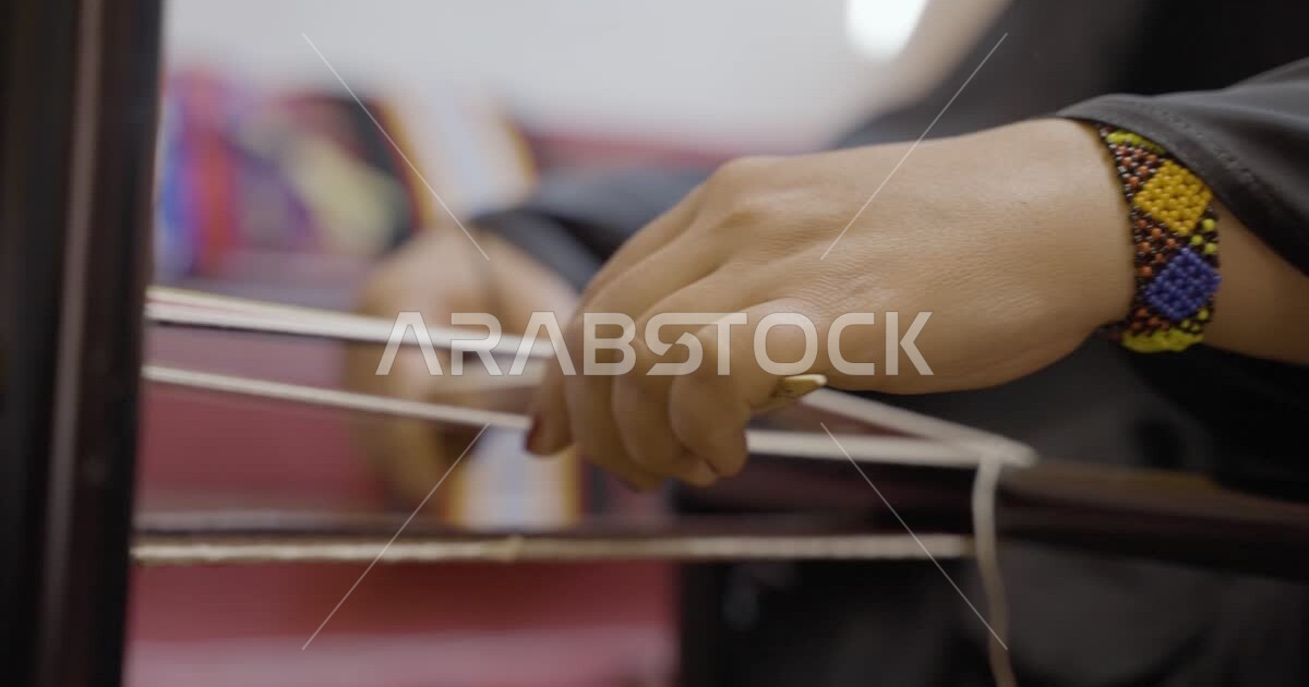 Close-up of the hand of a Saudi Arabian Gulf woman weaving and spinning ...