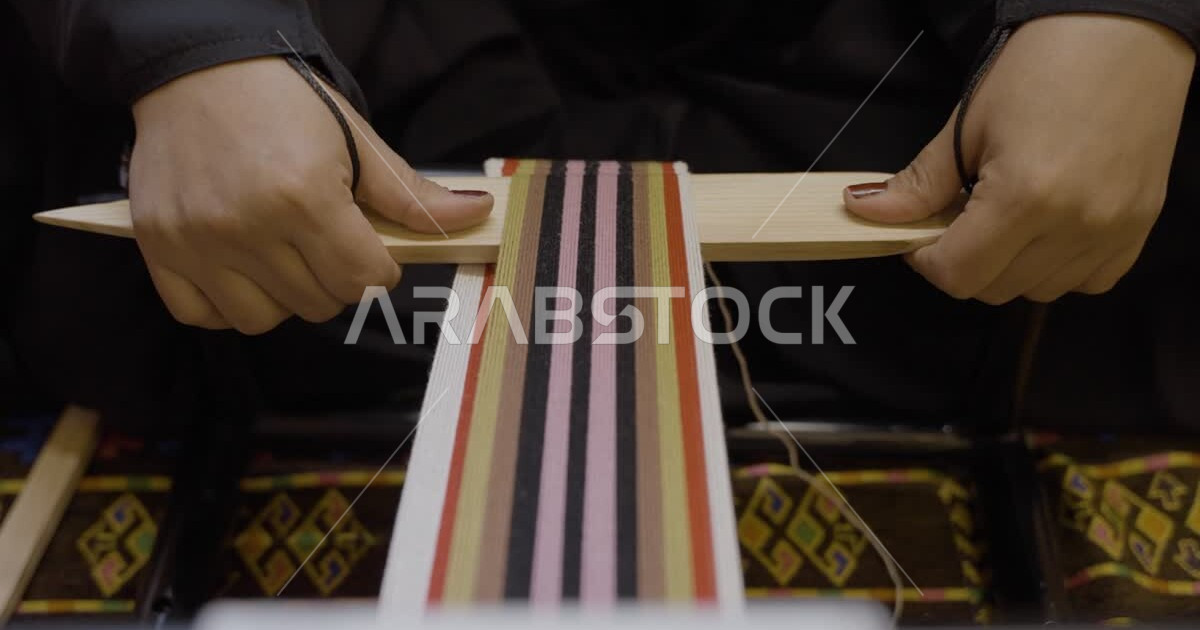 Close-up of the hand of a Saudi Arabian Gulf woman weaving and spinning ...