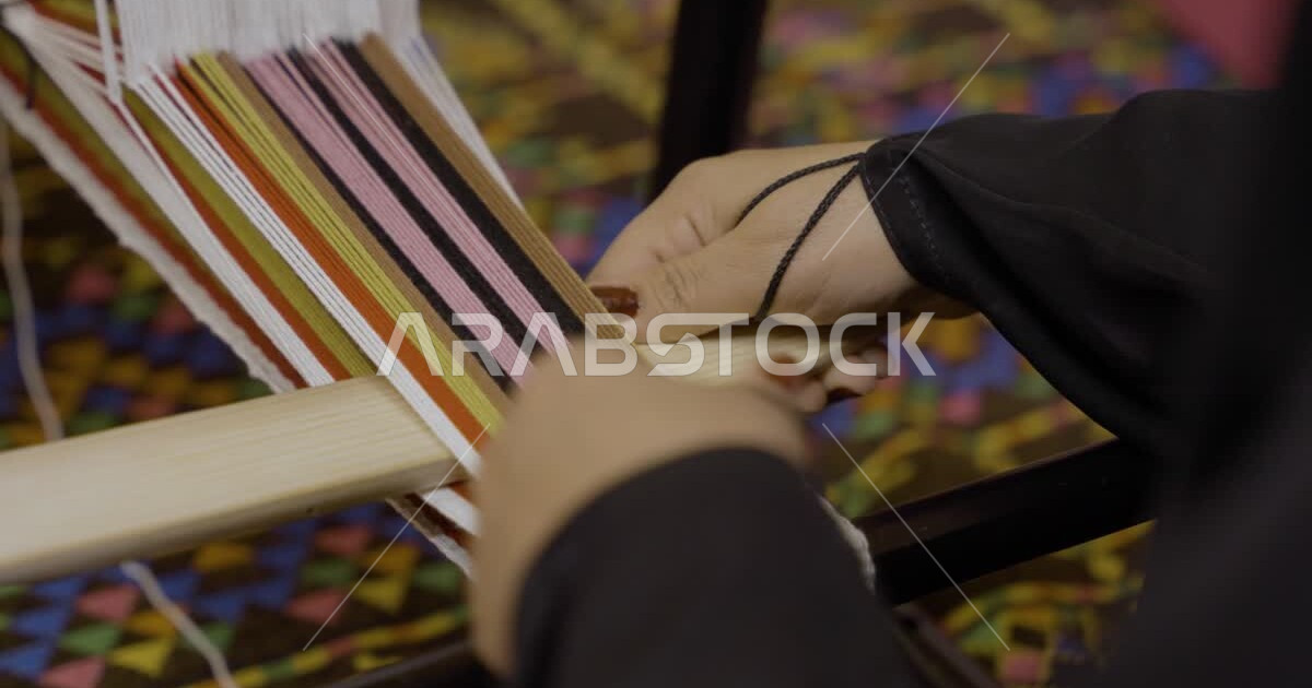 Close-up of the hand of a Saudi Arabian Gulf woman weaving and spinning ...