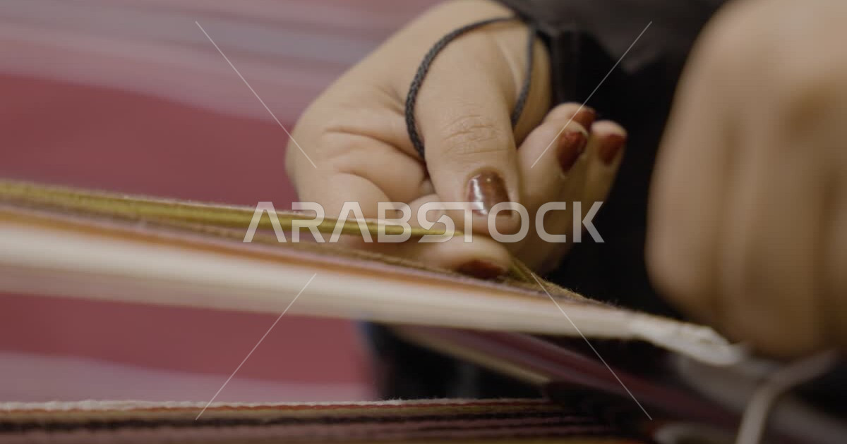 Close-up of the hand of a Saudi Arabian Gulf woman weaving and spinning ...