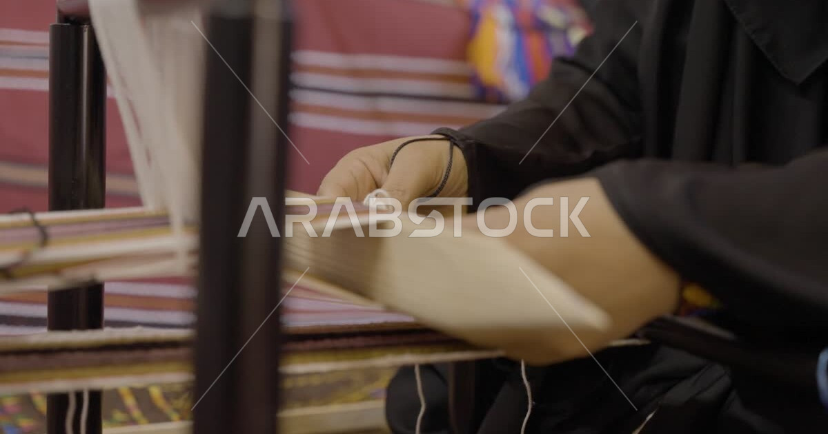 Close-up of the hand of a Saudi Arabian Gulf woman weaving and spinning ...