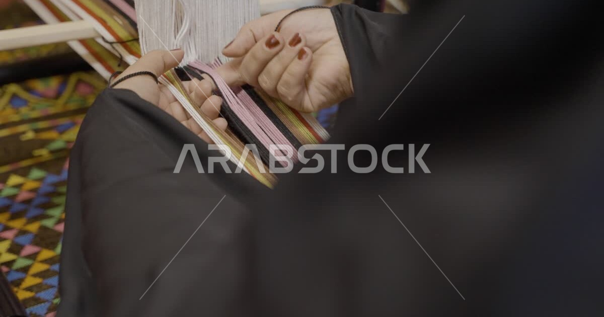 Close-up of the hand of a Saudi Arabian Gulf woman weaving and spinning ...