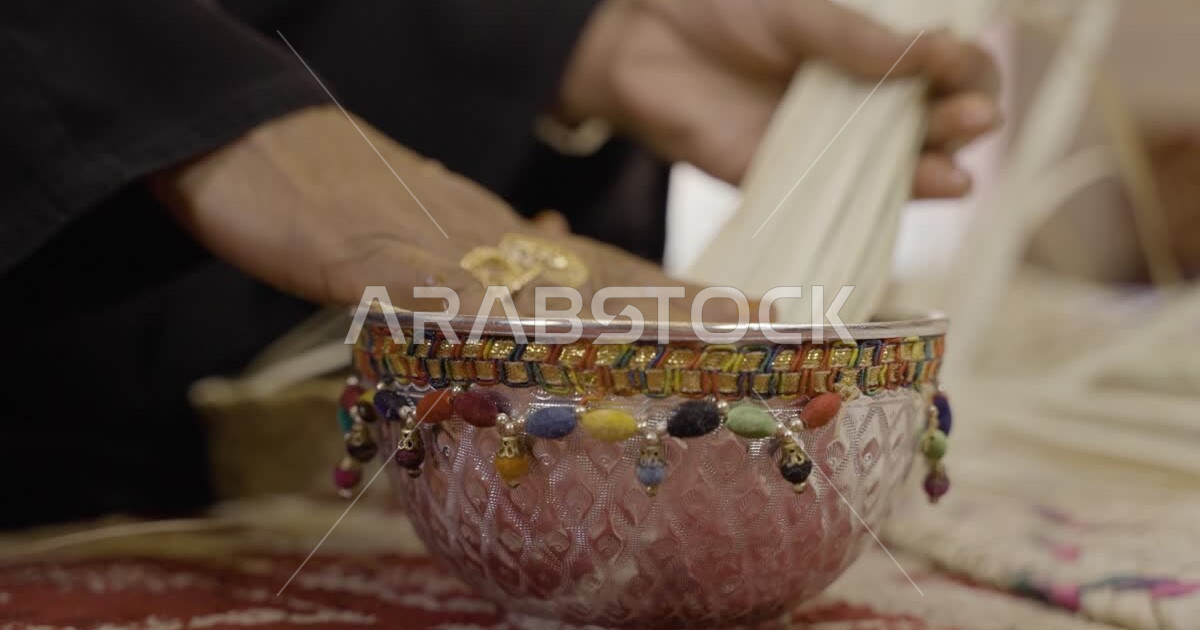 Close-up of the hand of a Saudi Arabian Gulf woman braiding wicker ...