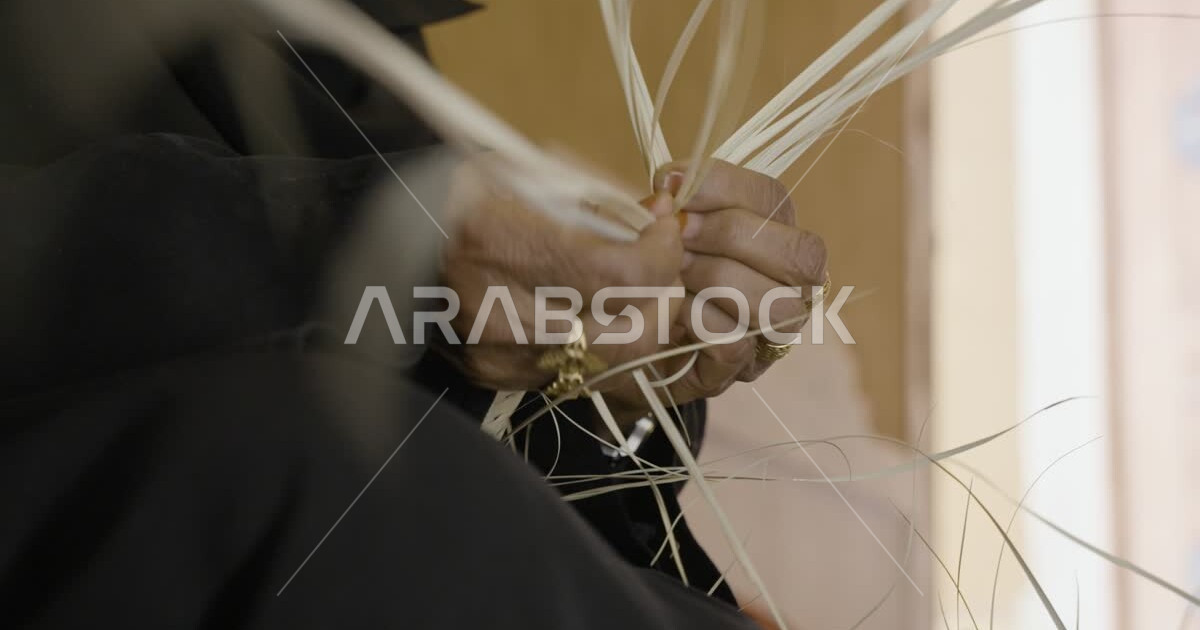 Close-up of the hand of a Saudi Arabian Gulf woman braiding wicker ...