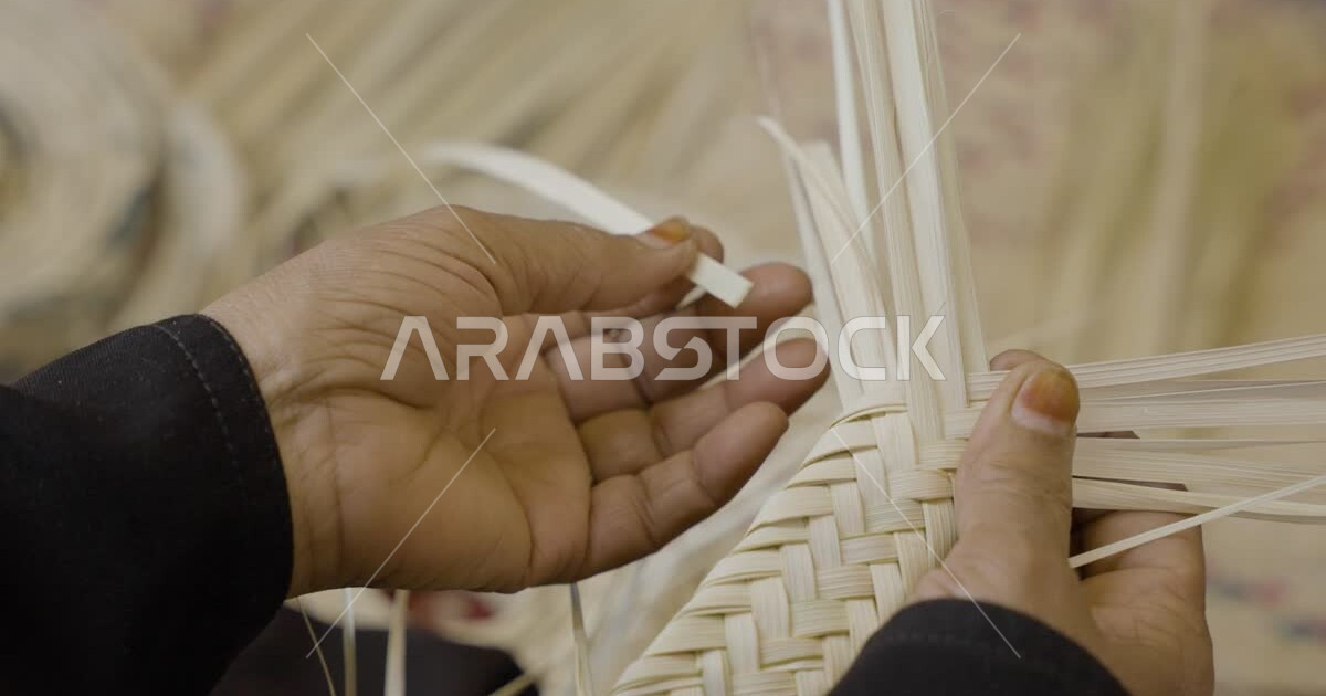 Close-up of the hand of a Saudi Arabian Gulf woman braiding wicker ...
