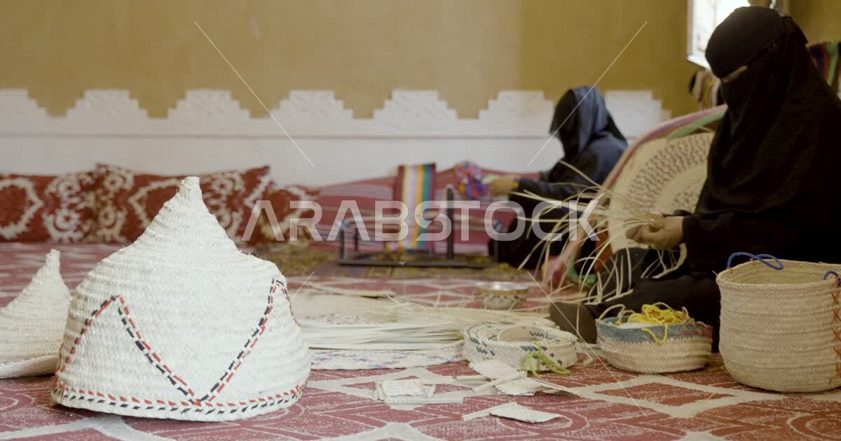 A Saudi Arab Gulf woman wearing a veil braids wicker palms, traditional ...