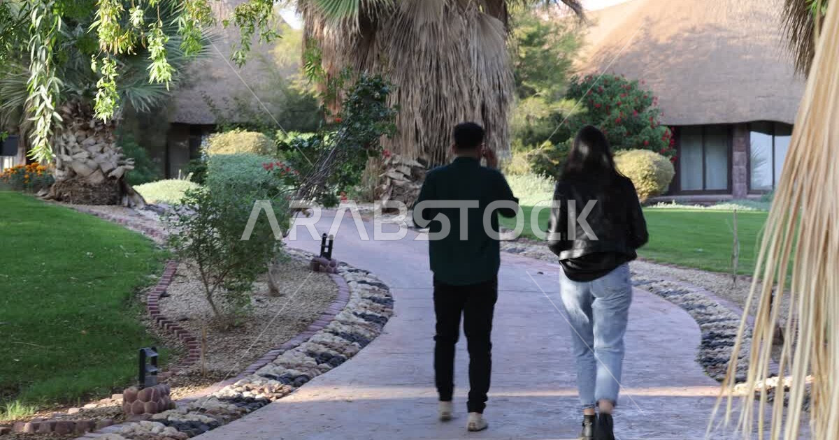 Photography from behind of a Saudi Arabian Gulf woman and man walking ...