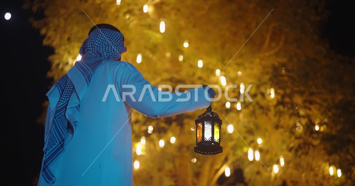 Saudi Arabian Gulf man holding a luminous lantern in his hand ...