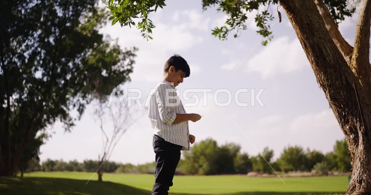 A Saudi Arabian Gulf boy in a public park, hiking in the open air ...