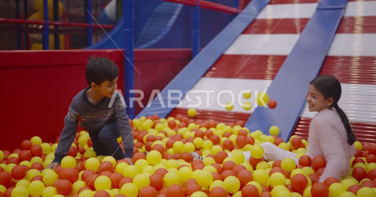 Two Saudi Arabian Gulf children enjoying playing on a skating game ...
