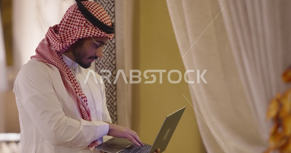 A Saudi Arabian Gulf man using a laptop, working remotely, using modern ...
