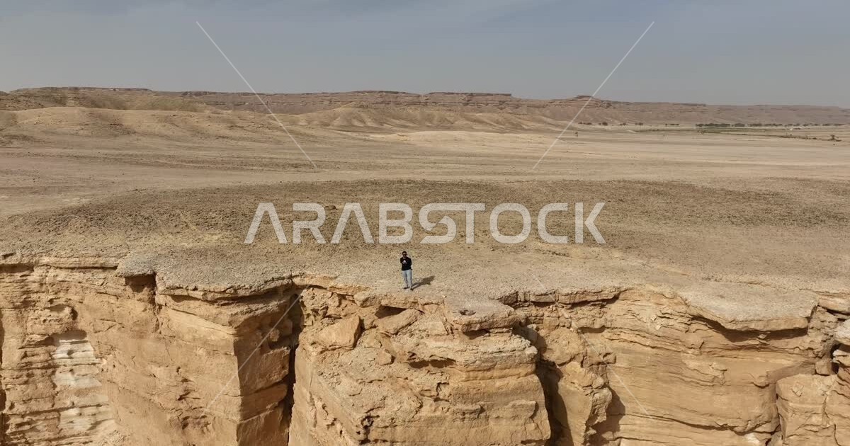 Drone photography of a tourist standing on the edge of Tuwaiq Mountain ...