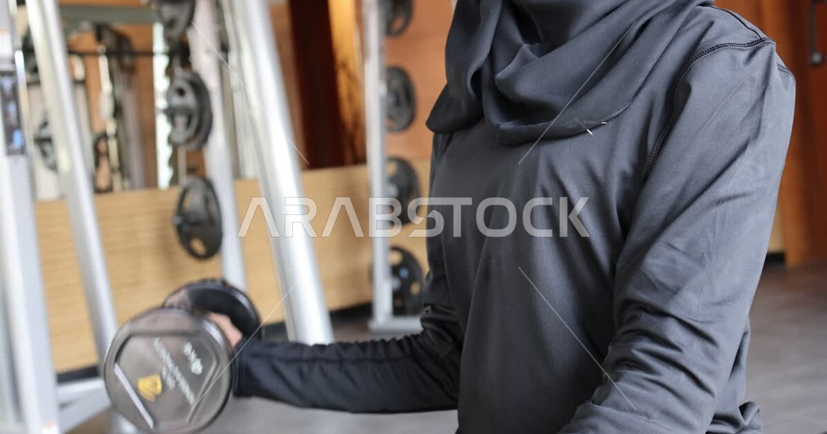A Saudi Arab woman in the gym, wearing sports clothes, exercising with ...